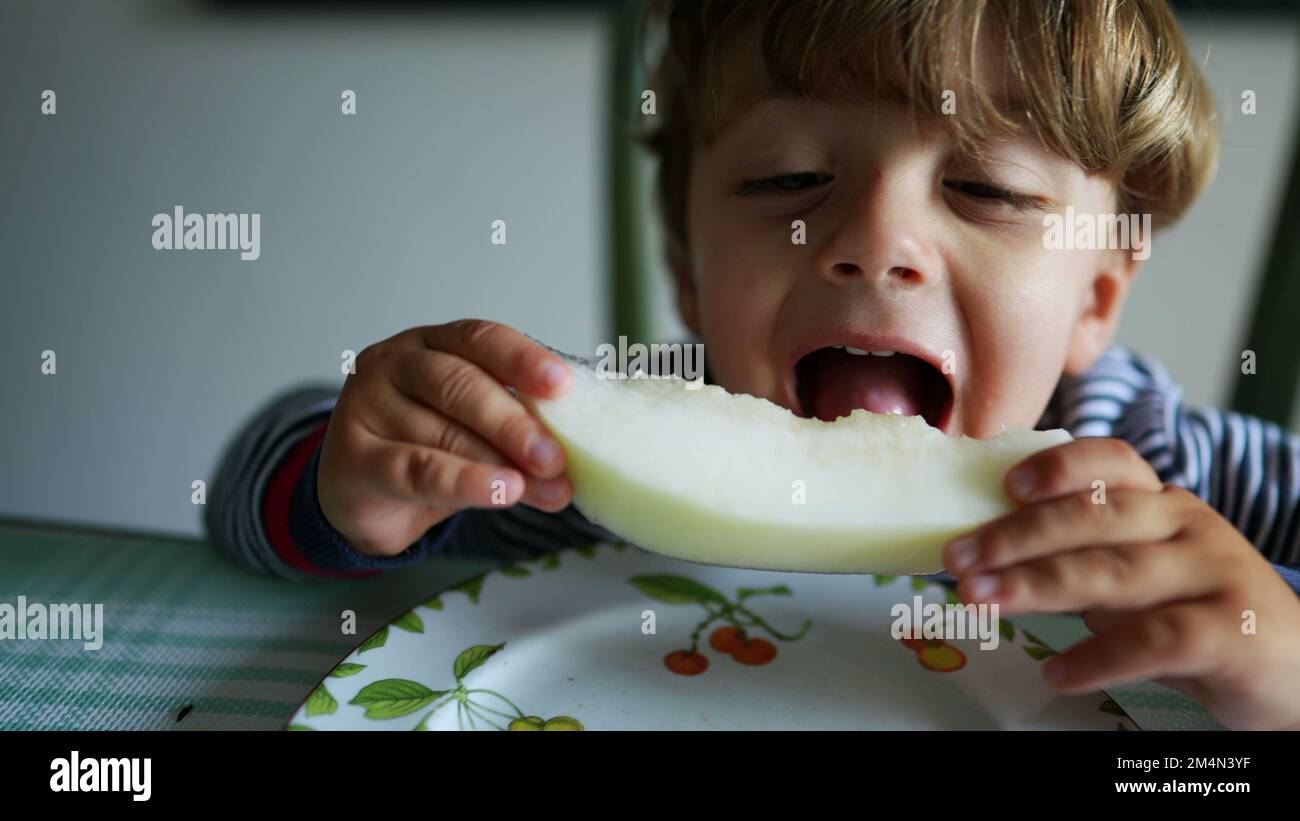 Child eating melon fruit hungry little boy eats healthy snack Stock ...