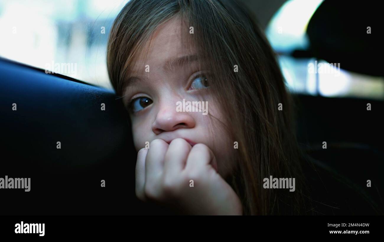 Sad little girl closeup face traveling by car leaning on car window ...