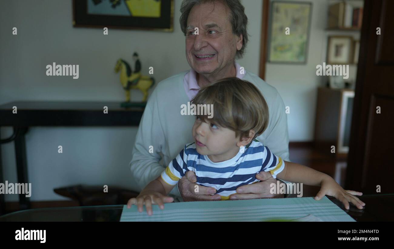 Grandson sitting on grandfather lap. Authentic real life family ...