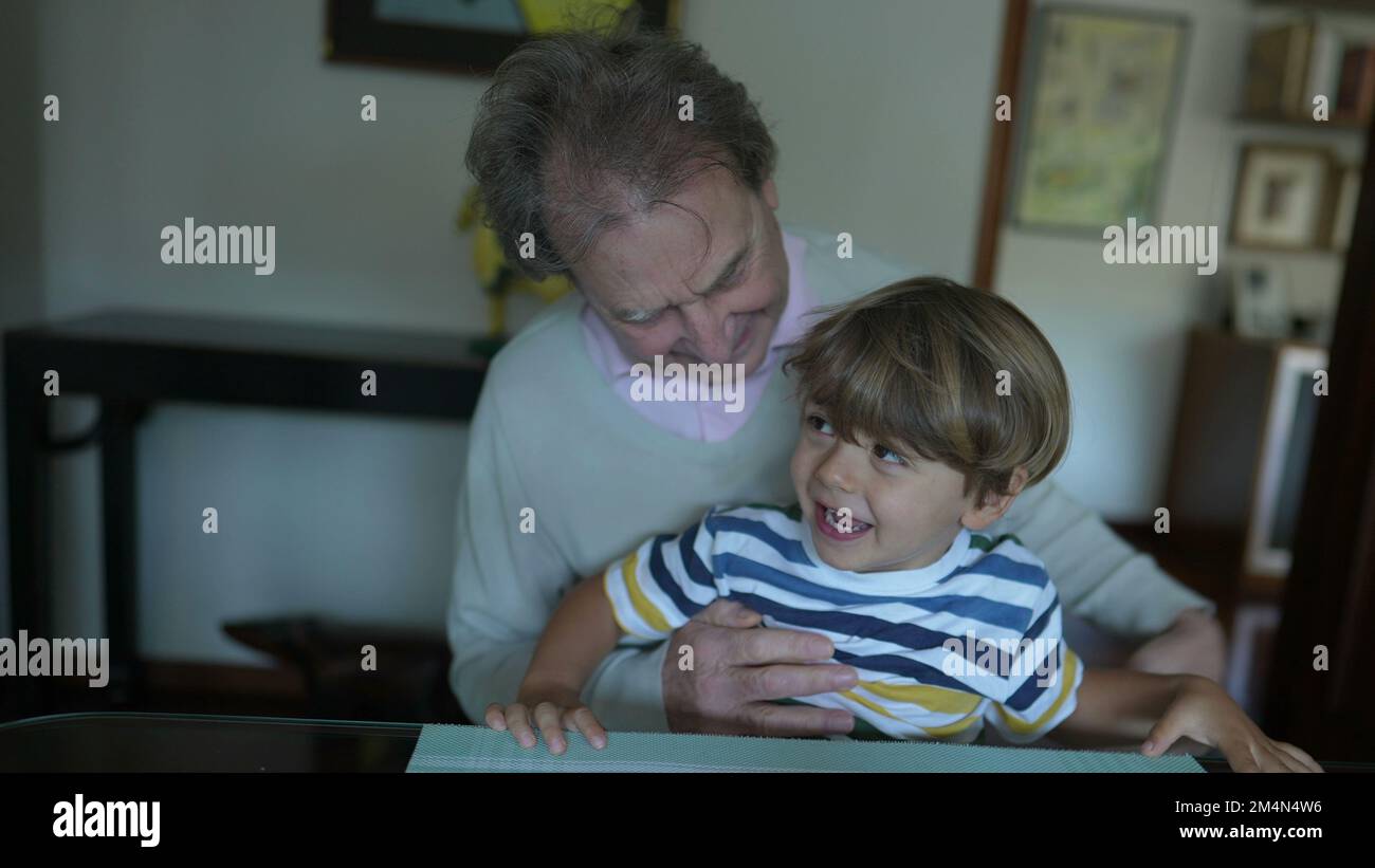 Grandson sitting on grandfather lap. Authentic real life family ...