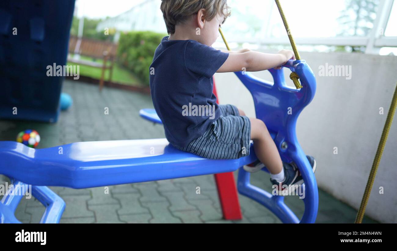 Little boy playing at playground child swinging in movement Stock Photo ...