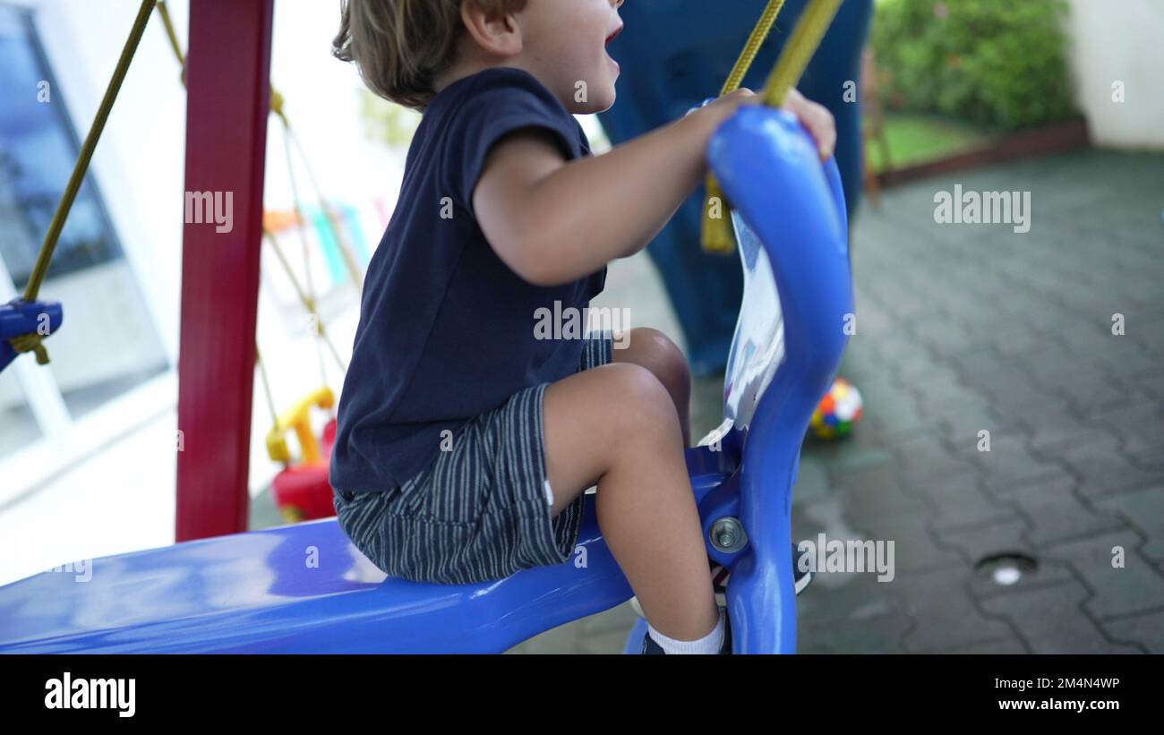 Little boy playing at playground child swinging in movement Stock Photo ...
