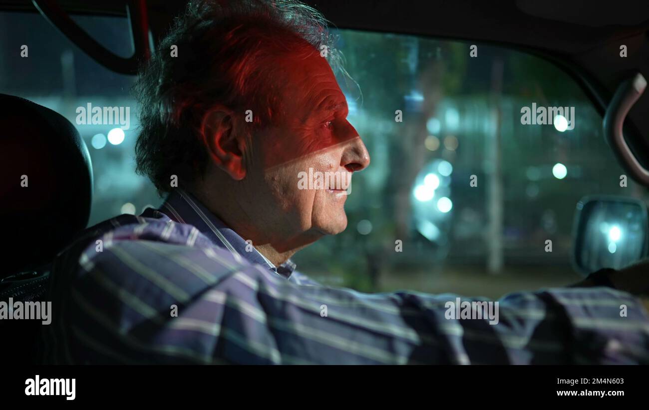 Older man driving at night in city. Profile closeup face of mature ...