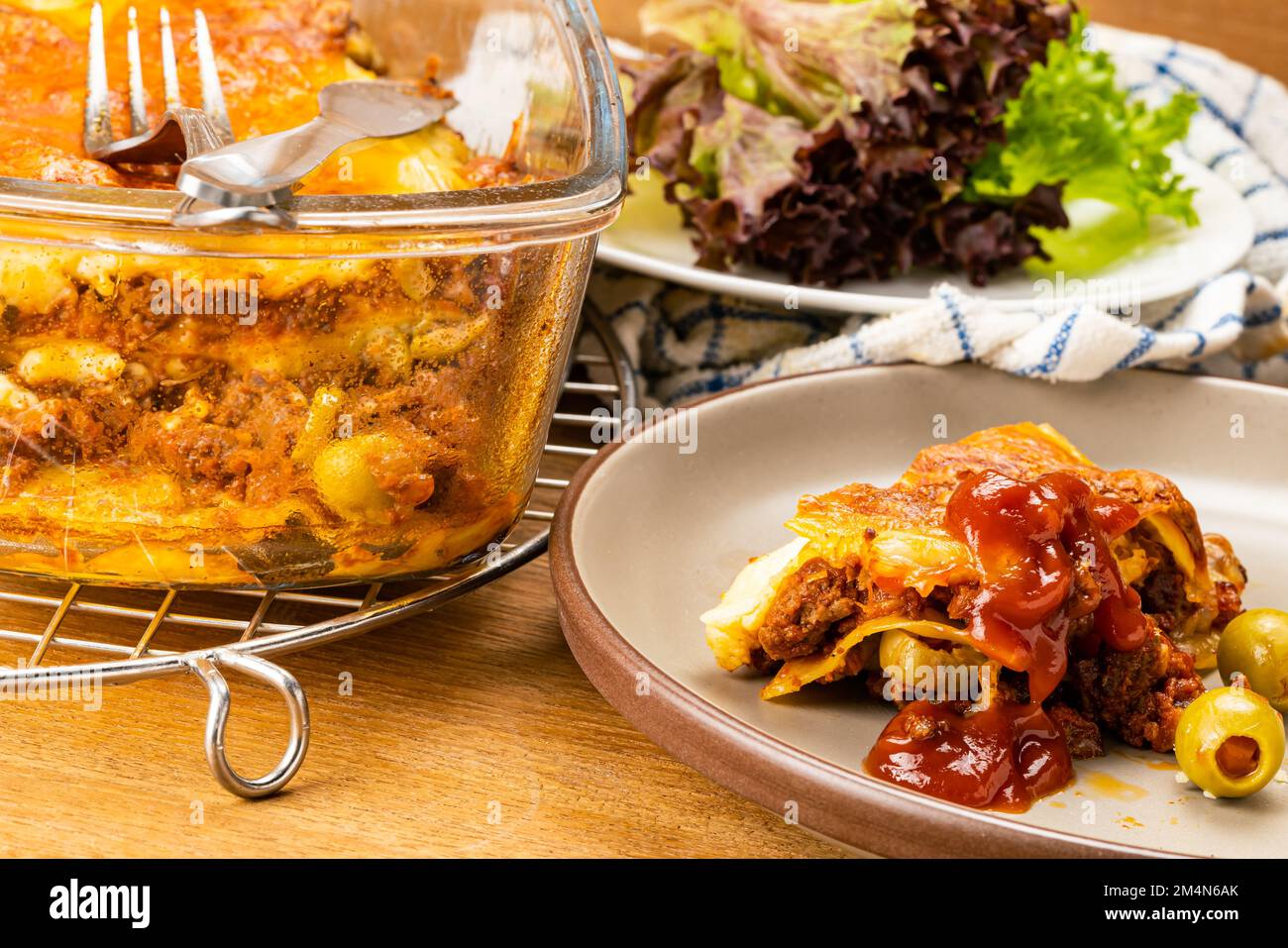 Piece of delicious homemade lasagna in brown ceramic dish with lasagna ...