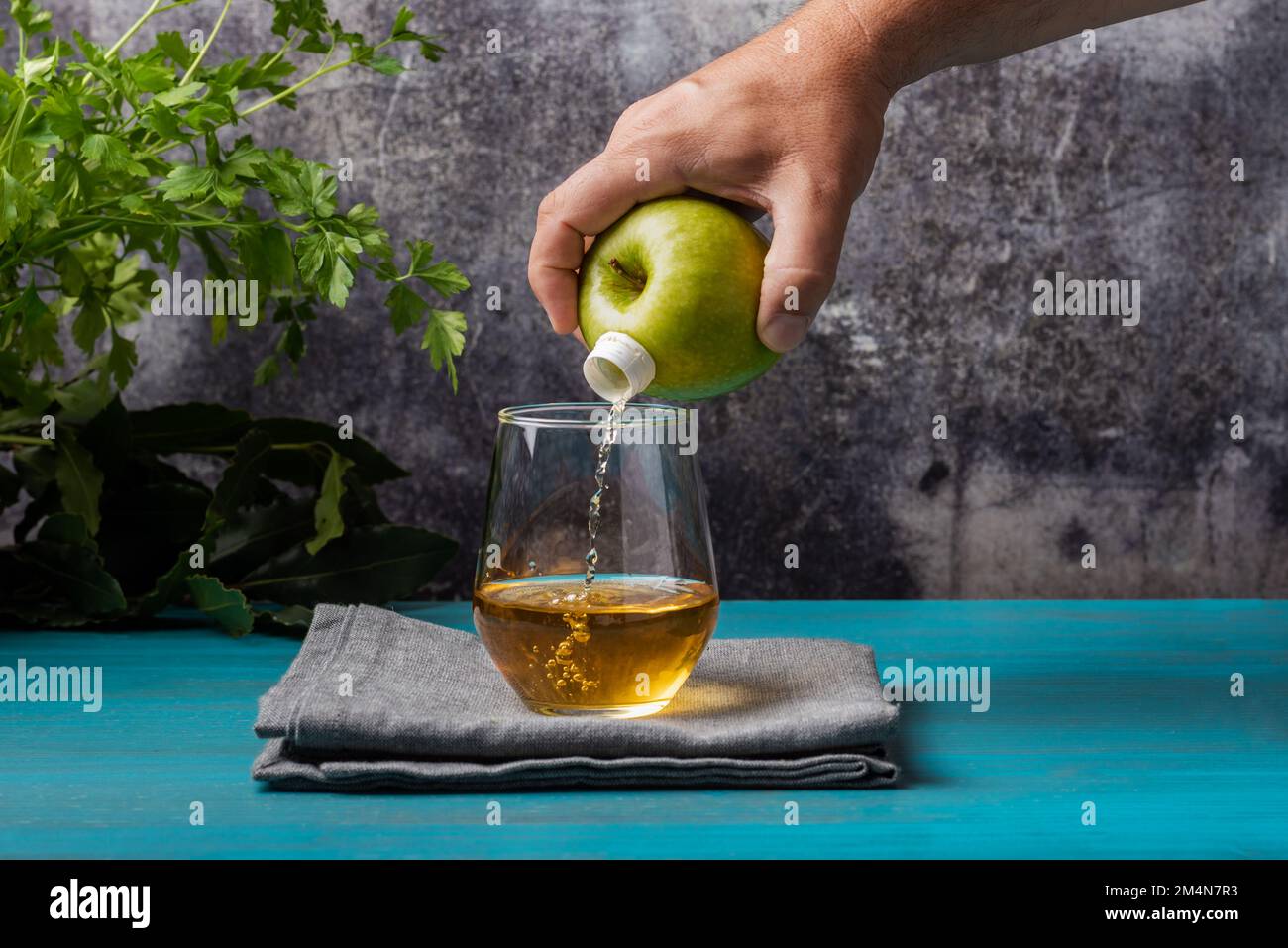 Hand holding a fruit, a green apple, which has a spout through which it ...