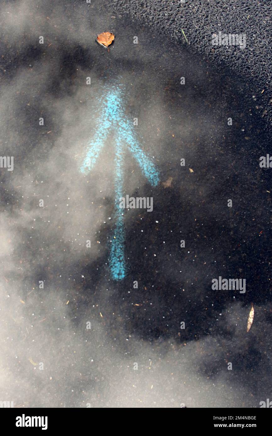 Painted arrow on tarmac under a puddle with smoke drifting across Stock ...