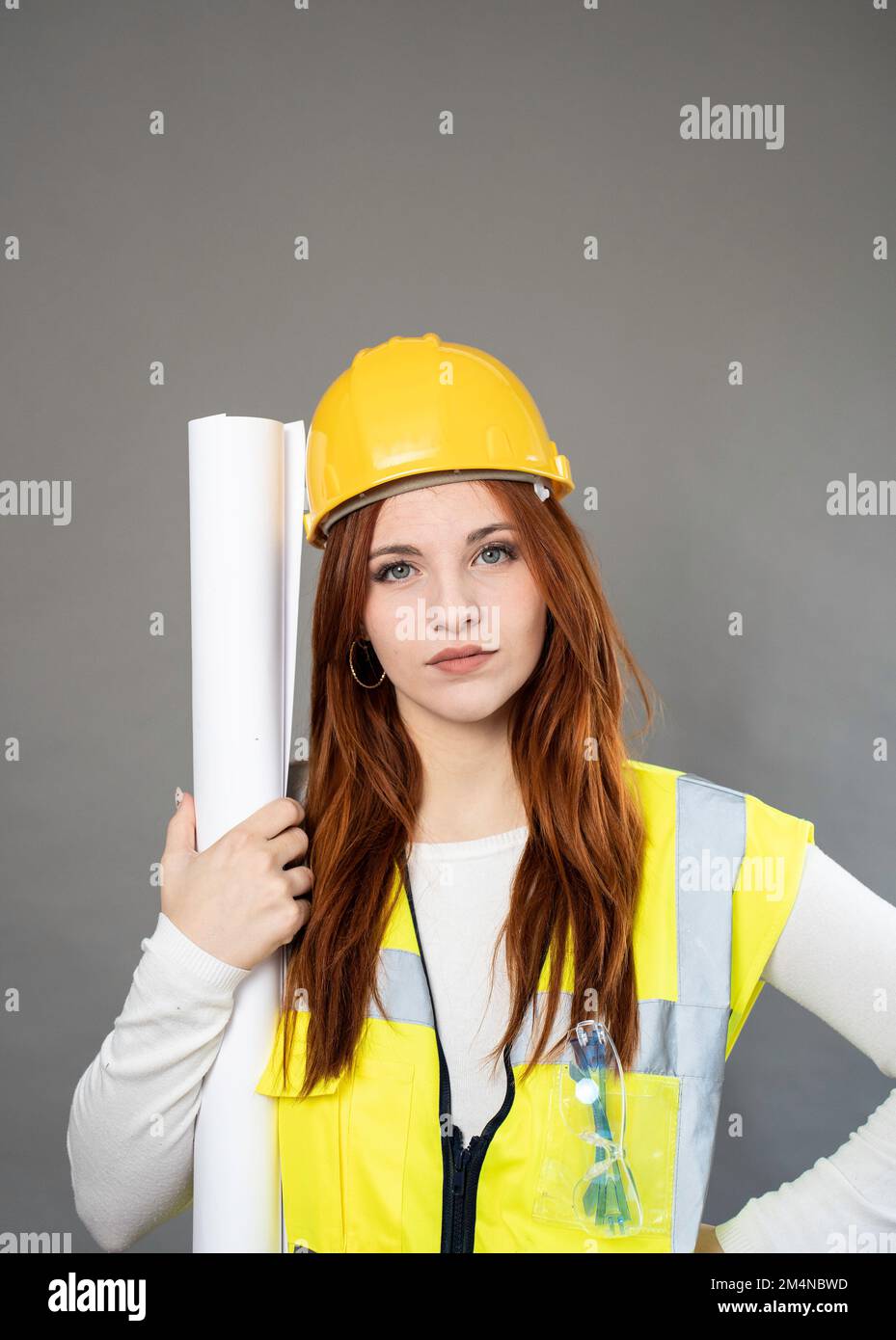 Young female redhead engineer or worker of construction site with paper ...