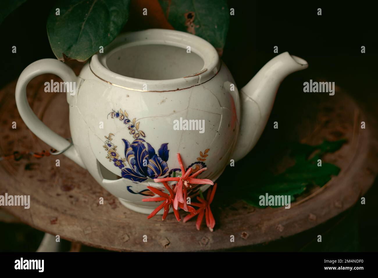 A closeup shot of a Broken porcelain tea kettle decorated with flowers ...