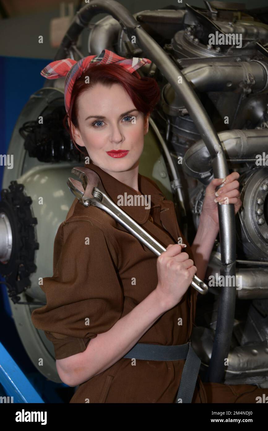 Model posing as 'Rosie the riviter' style vintage WW2 aircraft engine ...