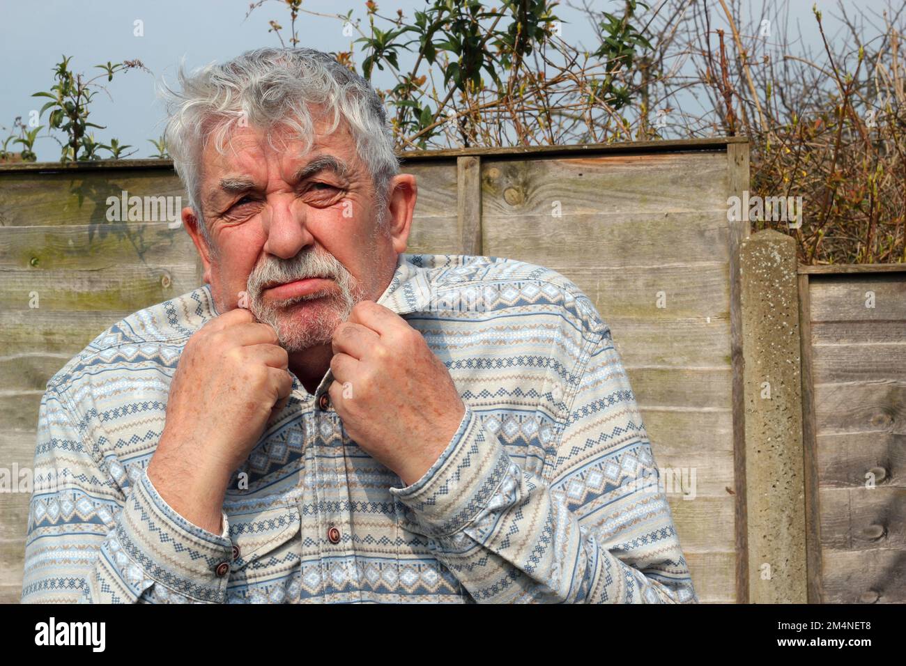 Senior or old man very cold. pulling shirt collar up because he is ...