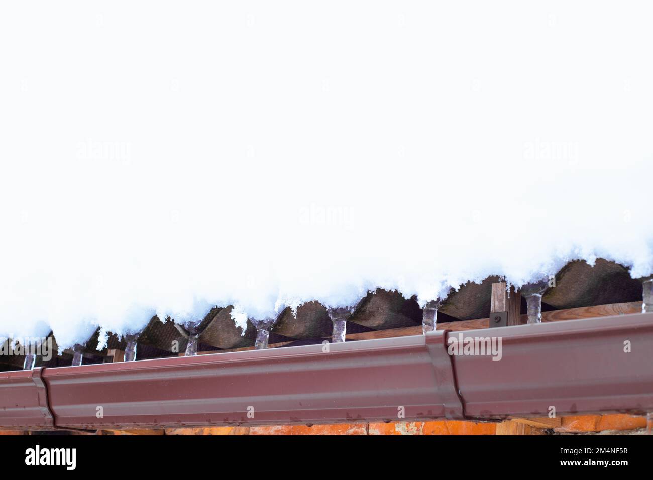 Snow drifts on the roof and icicles hanging over the gutter Stock Photo ...