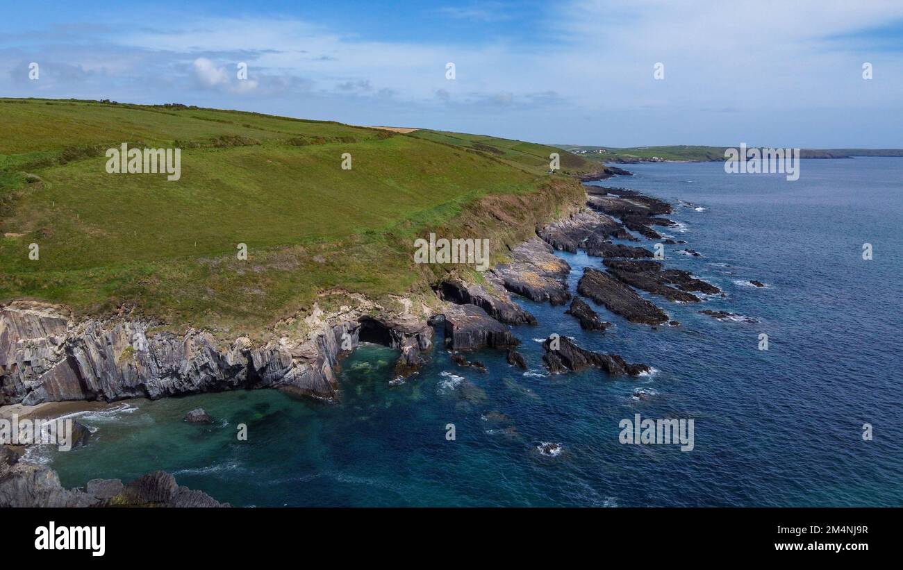 Vegetation-covered rocks on the shore of the Celtic Sea near the town ...