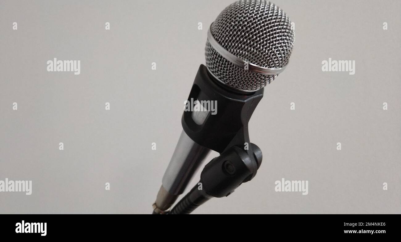 A microphone on a stand against a white wall background Stock Photo - Alamy