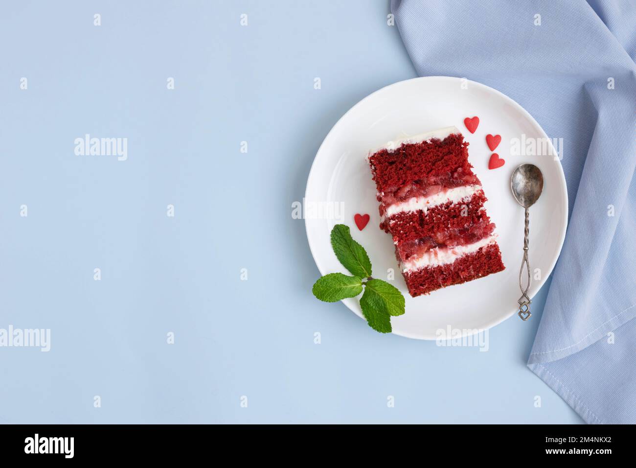 A piece of red velvet sponge cake white plate with hearts, blue ...