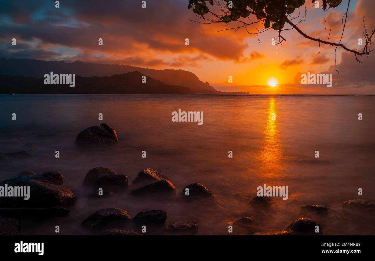 The slanting rays of the sunset at a beach with the silhouette of ...