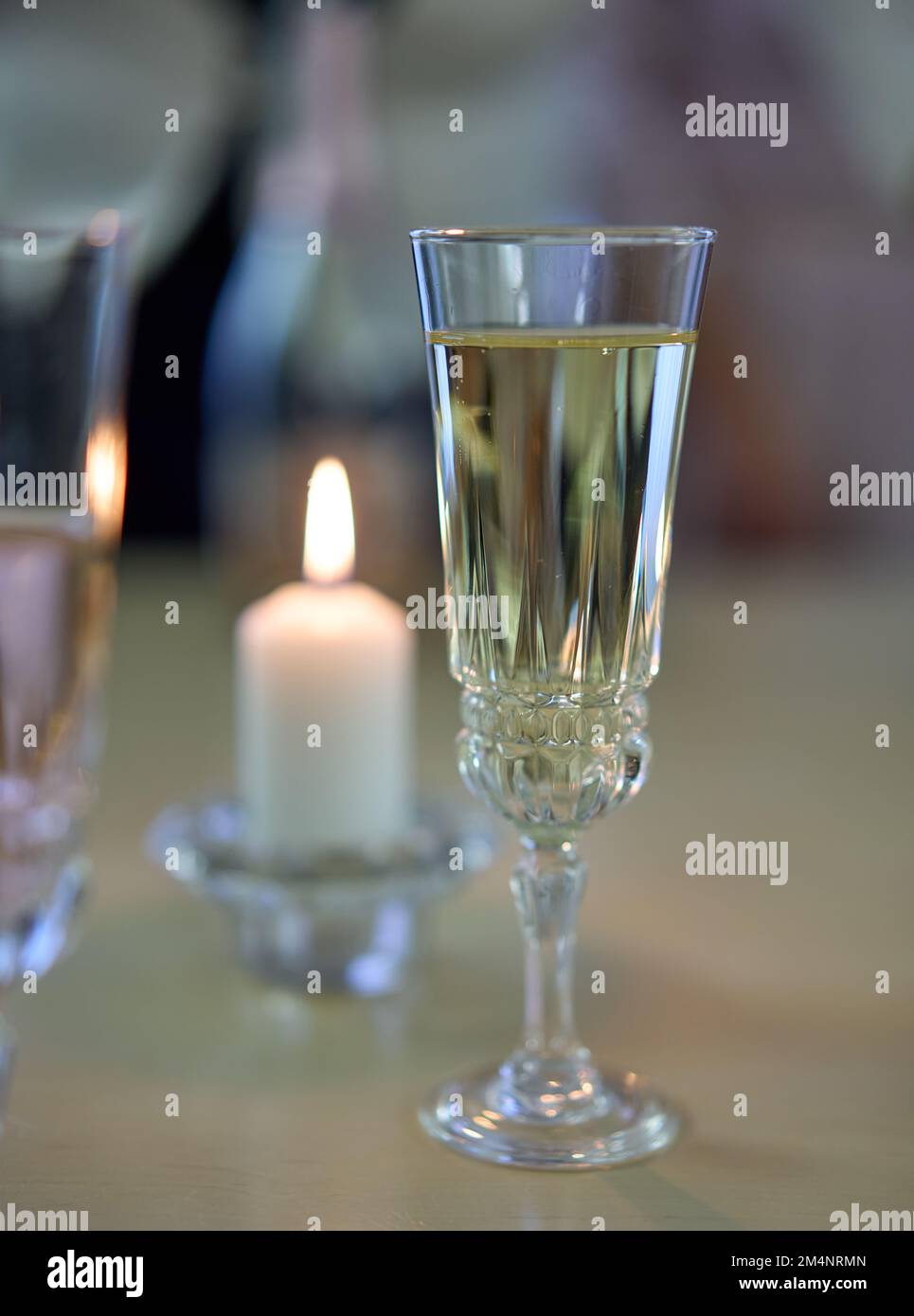 A glass of champagne and burning candle on the table. Selective focus ...