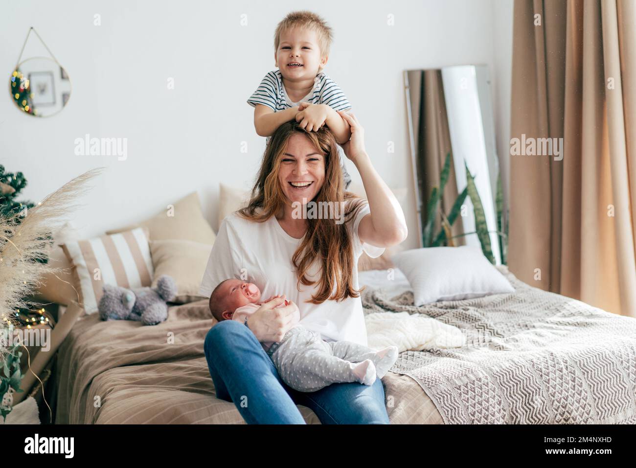 Cheerful mom with two children laughs and hugs and fools around on the ...