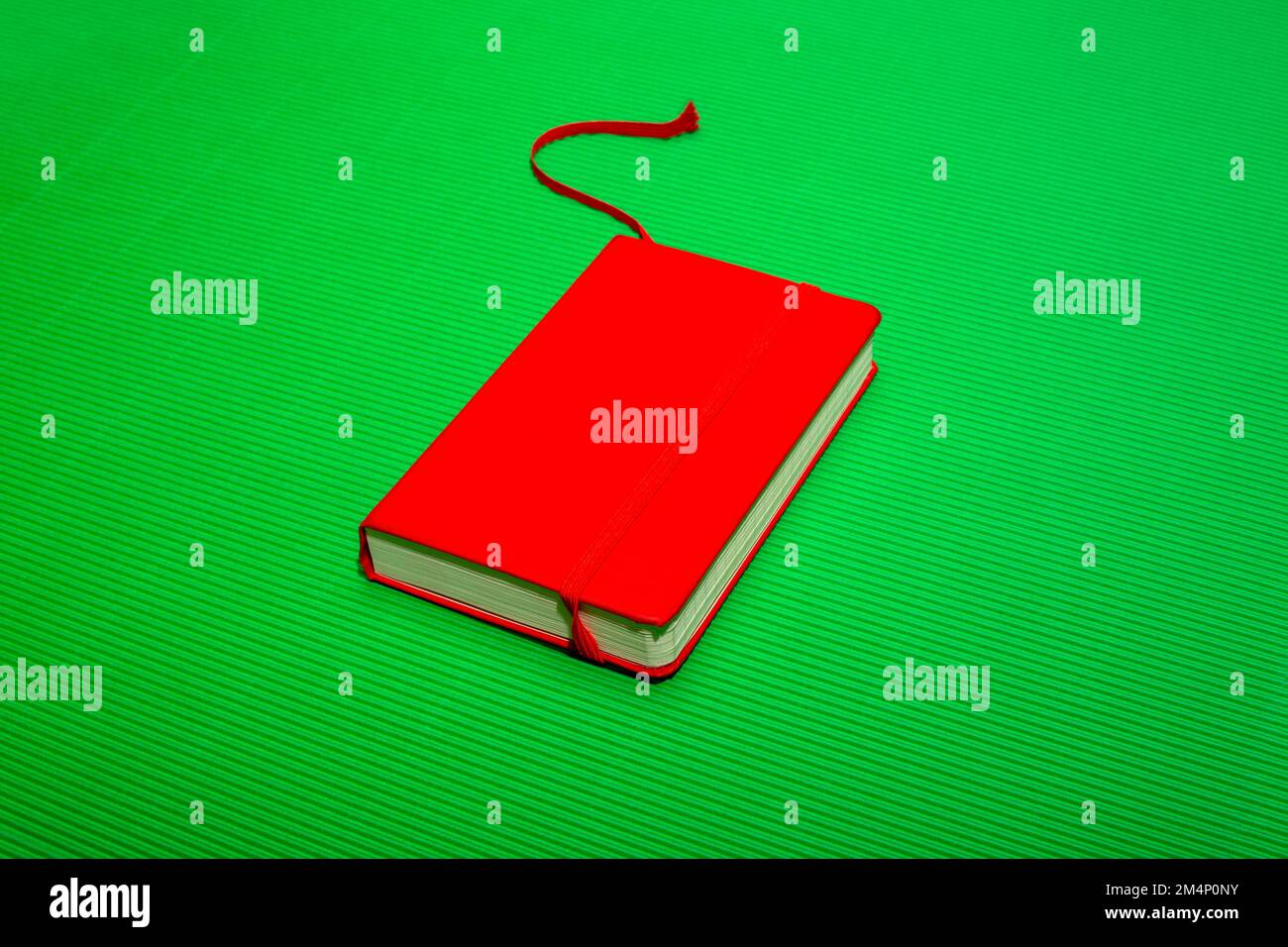 Red notebook with a bookmark on a green background Stock Photo - Alamy
