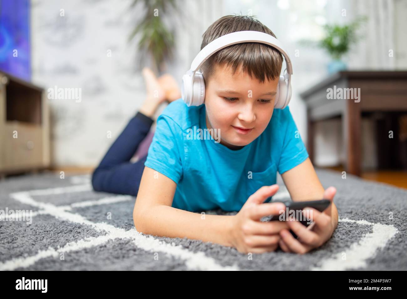 A child boy with phone and headphones is lying on the floor Stock Photo ...