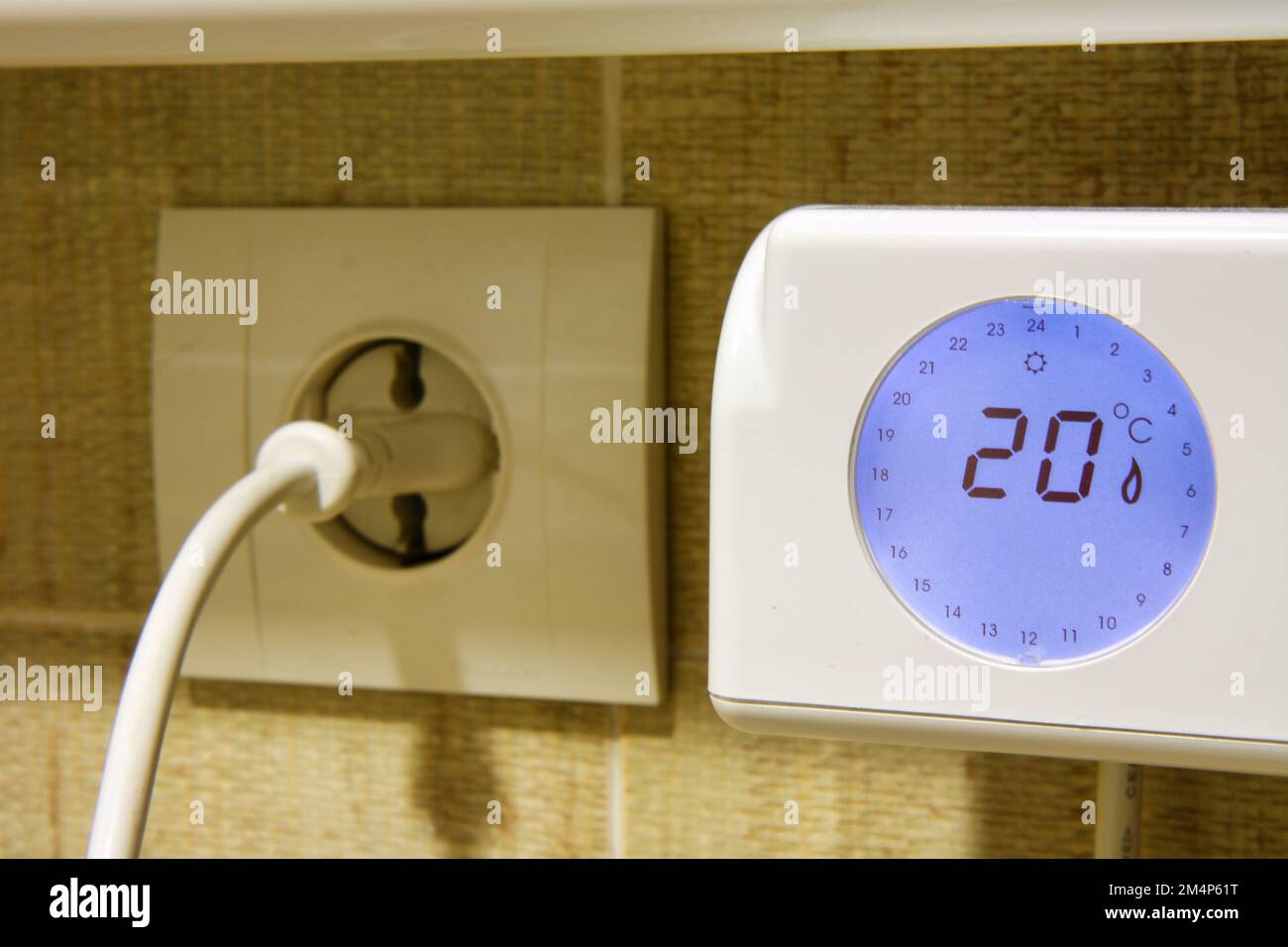 Detail of the thermostat and a plug of an electric heater at 20 degrees ...