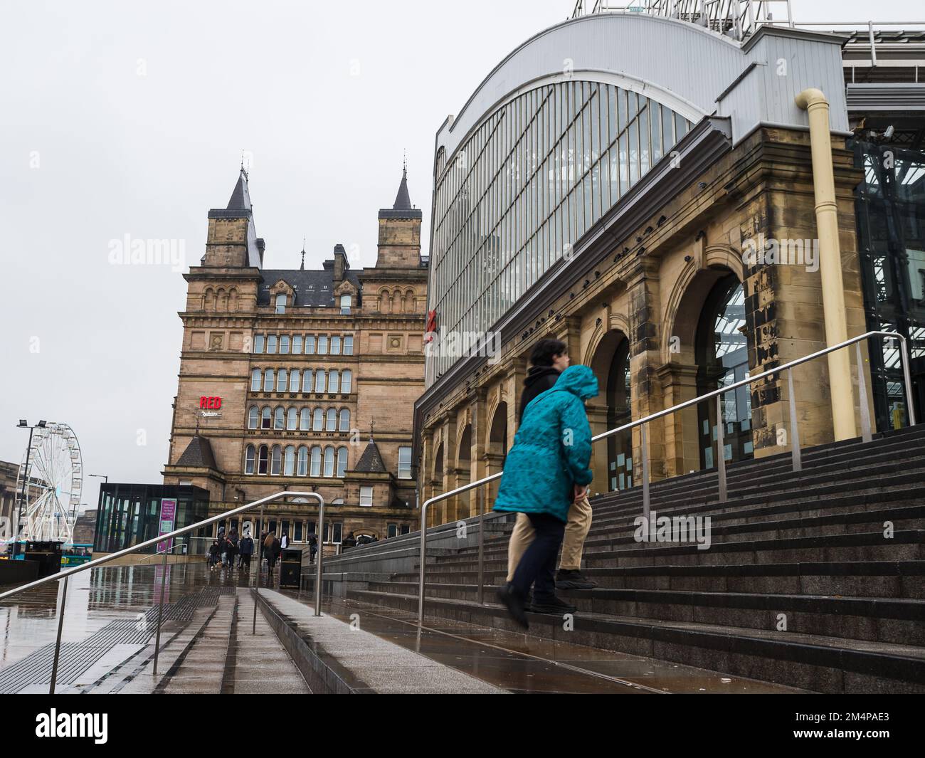A man and woman walk up the wet steps under a rainy sky towards ...