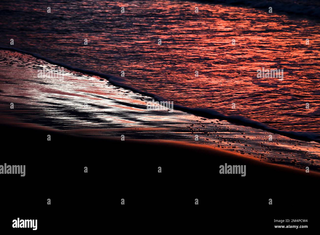 Colorful texture of waves on the beach at sunrise Stock Photo - Alamy