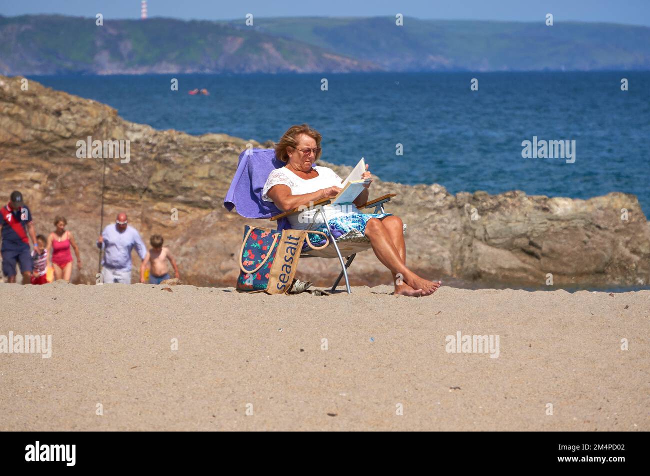 Woman reading a newspaper on a beach in Cornwall, UK Stock Photo - Alamy