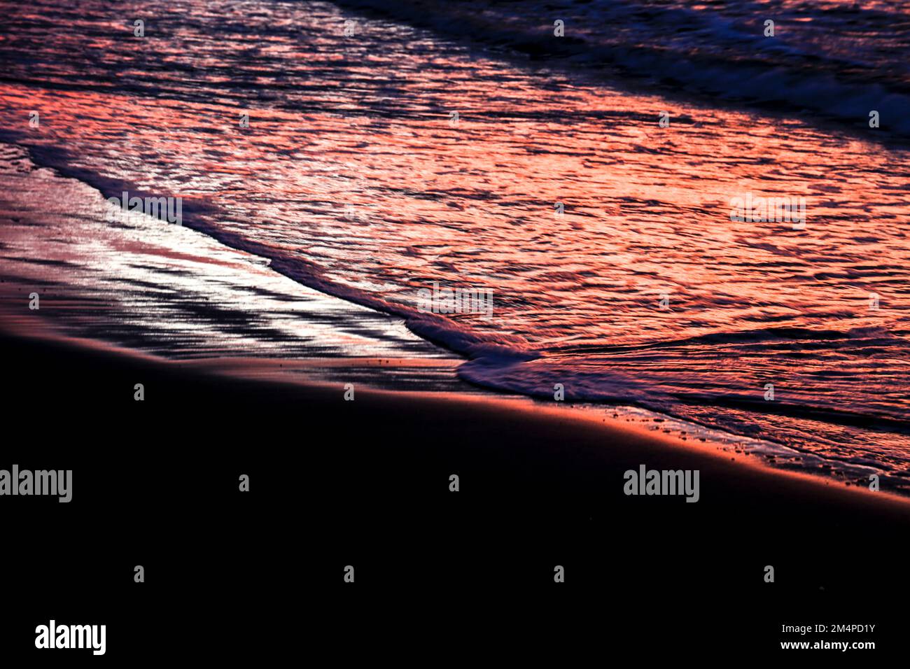 Colorful texture of waves on the beach at sunrise Stock Photo - Alamy