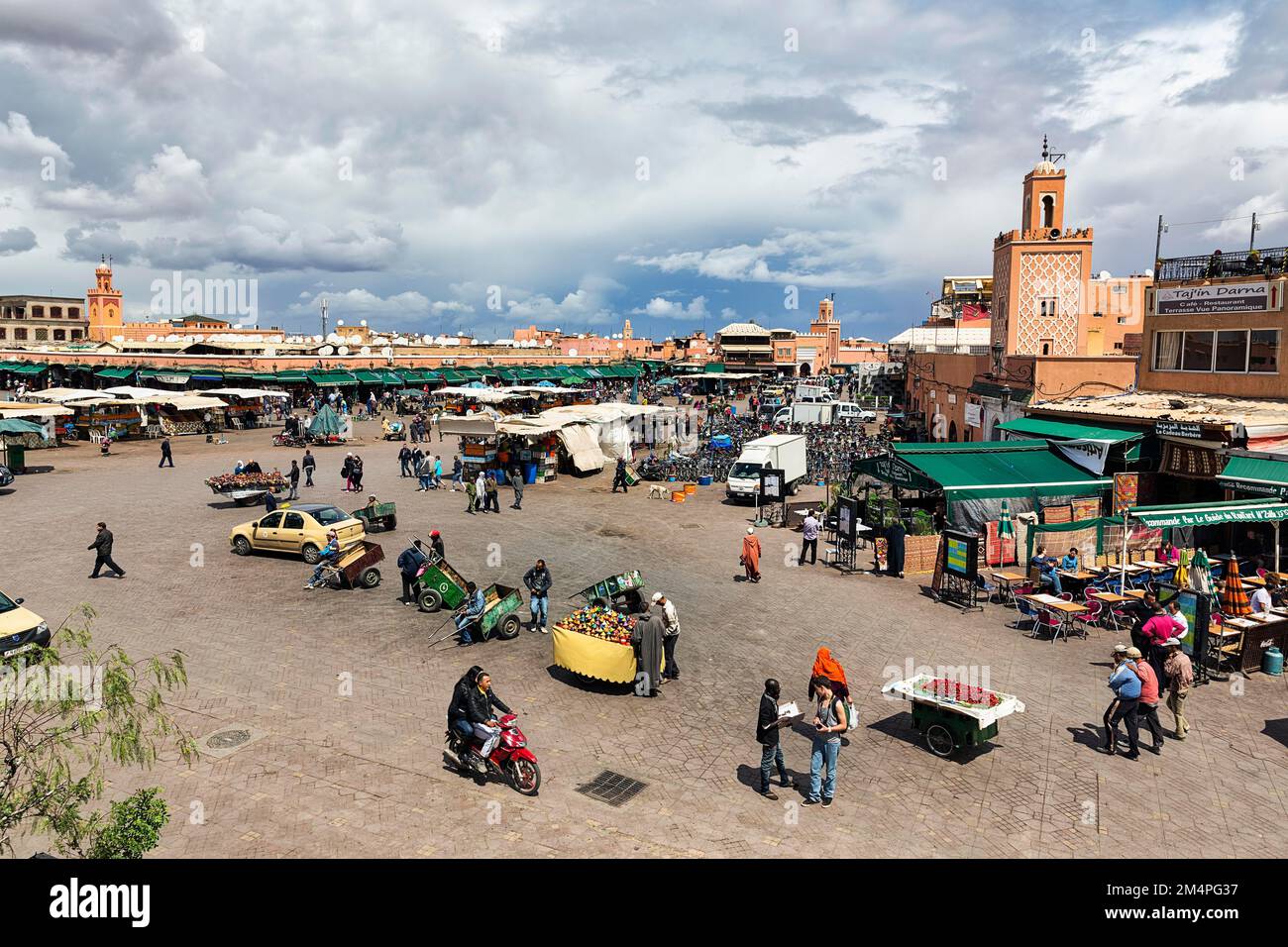 Market stalls, passers-by and vehicles in the bustling Djemaa el Fna ...