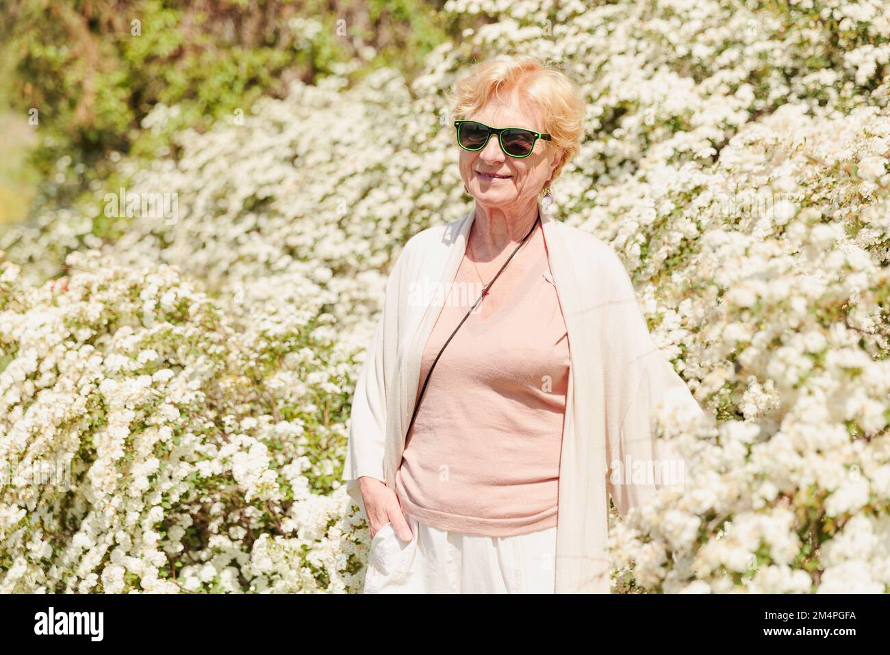 Elderly woman posing among bushes with white flowers Stock Photo - Alamy