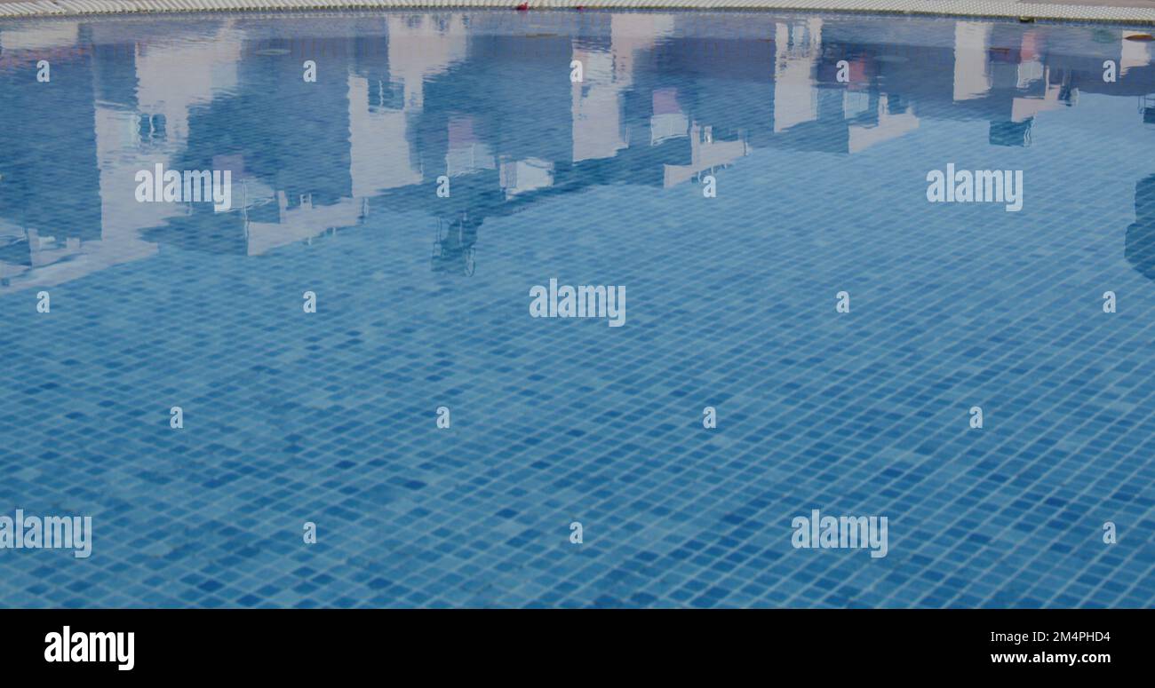 Empty swimming pool with blue clean water. Reflection of buildings in ...