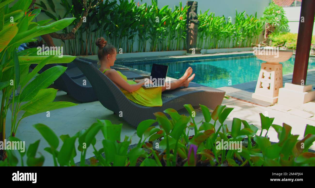 Girl finish working on laptop relaxing by the swimming pool. Remote job ...
