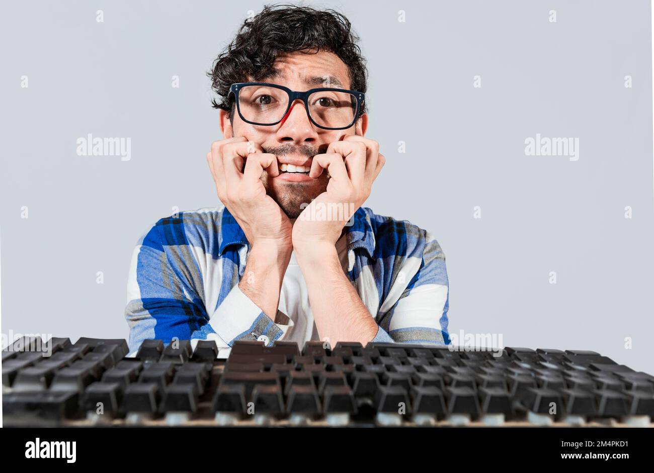 Nervous nerdy guy biting his nails in front of the keyboard, Worried ...