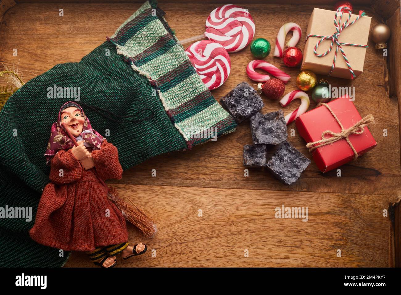 The Befana with sweet coal and candy on wooden background. Italian ...