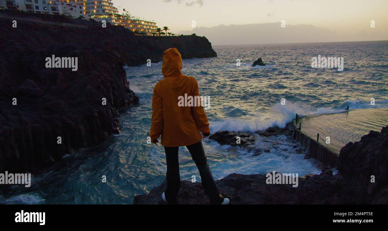 Woman enjoying ocean view at dusk or twilight, storm and wind weather ...