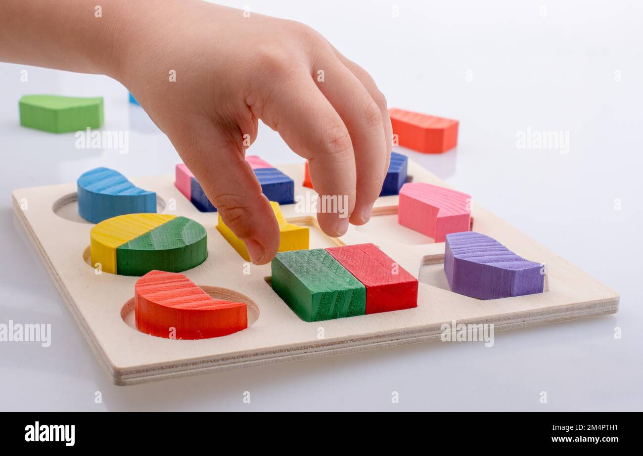 Colorful wooden pieces of a logic puzzle in hand Stock Photo - Alamy