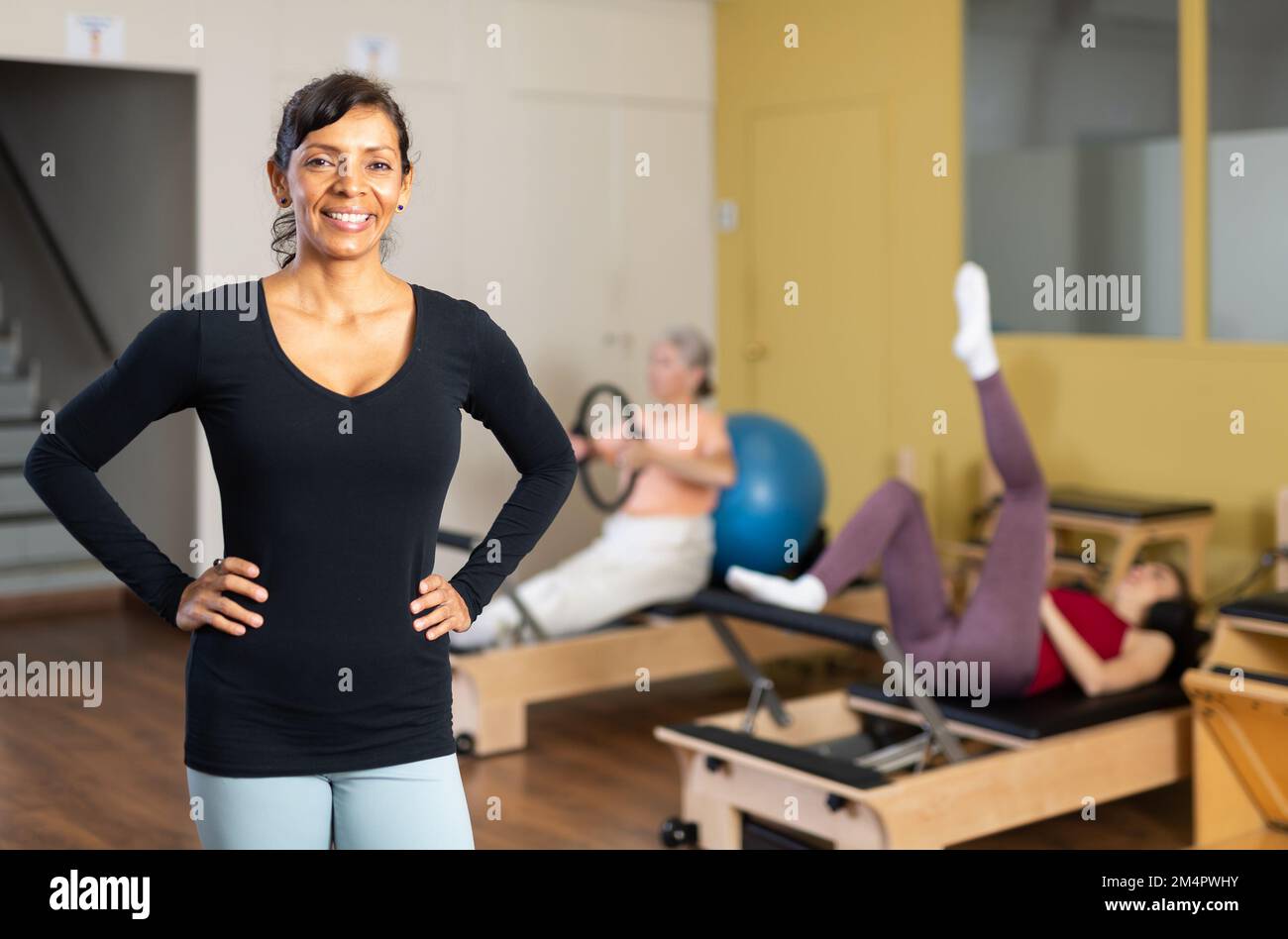 Smiling Hispanic woman standing akimbo in pilates studio Stock Photo ...