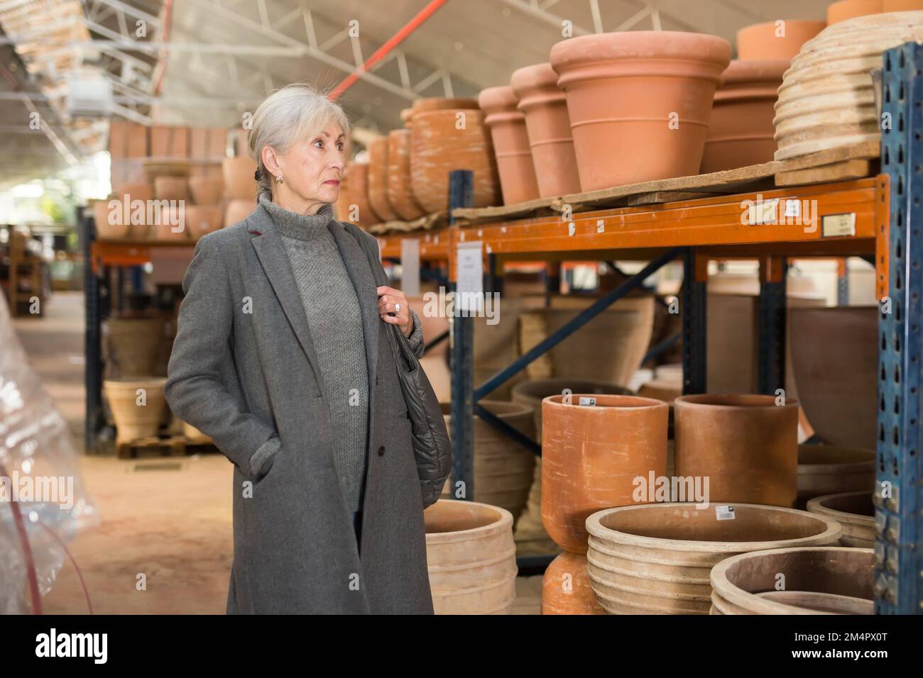 Aged woman choosing pots for house plants in gardening market Stock ...