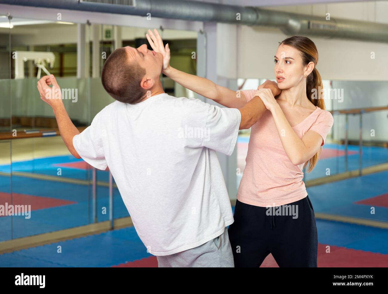 Young woman practicing palm strike with man in self defense training ...