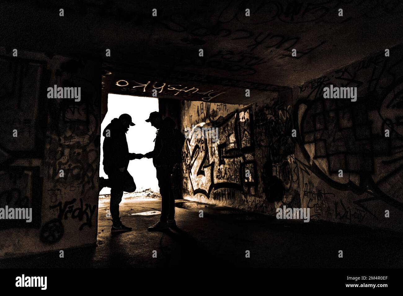 Two men as silhouette in bunker with graffiti walls, black and white ...