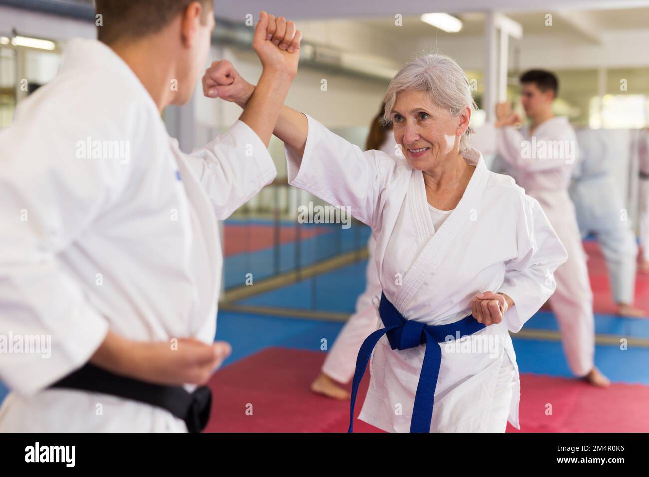 Man and senior woman sparring during group karate training Stock Photo ...