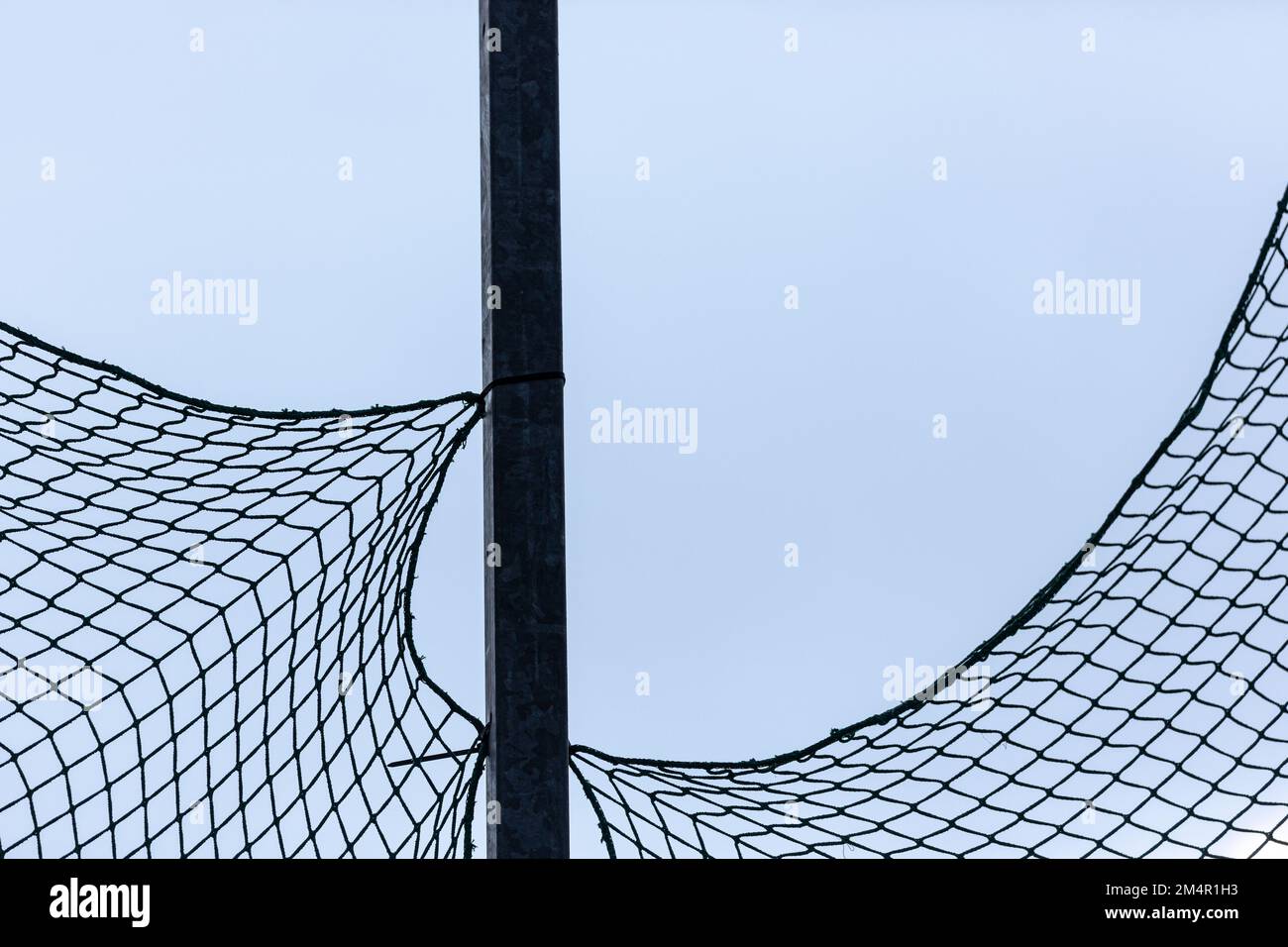 A rough net is tied to a pole against a blue sky Stock Photo - Alamy