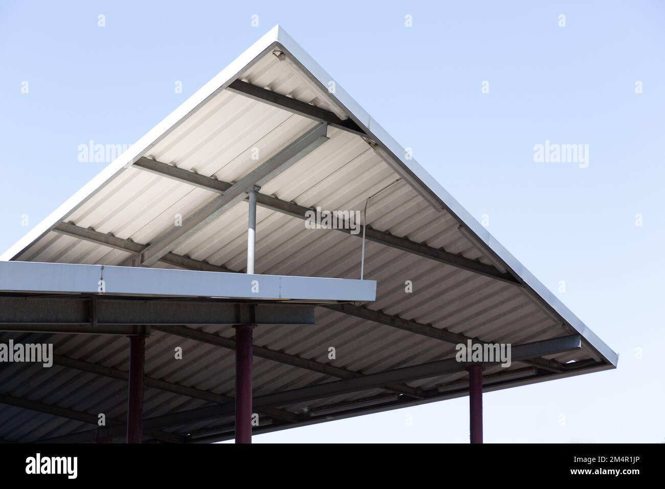 The corner of an old metal roof structure juts up into the blue sky ...
