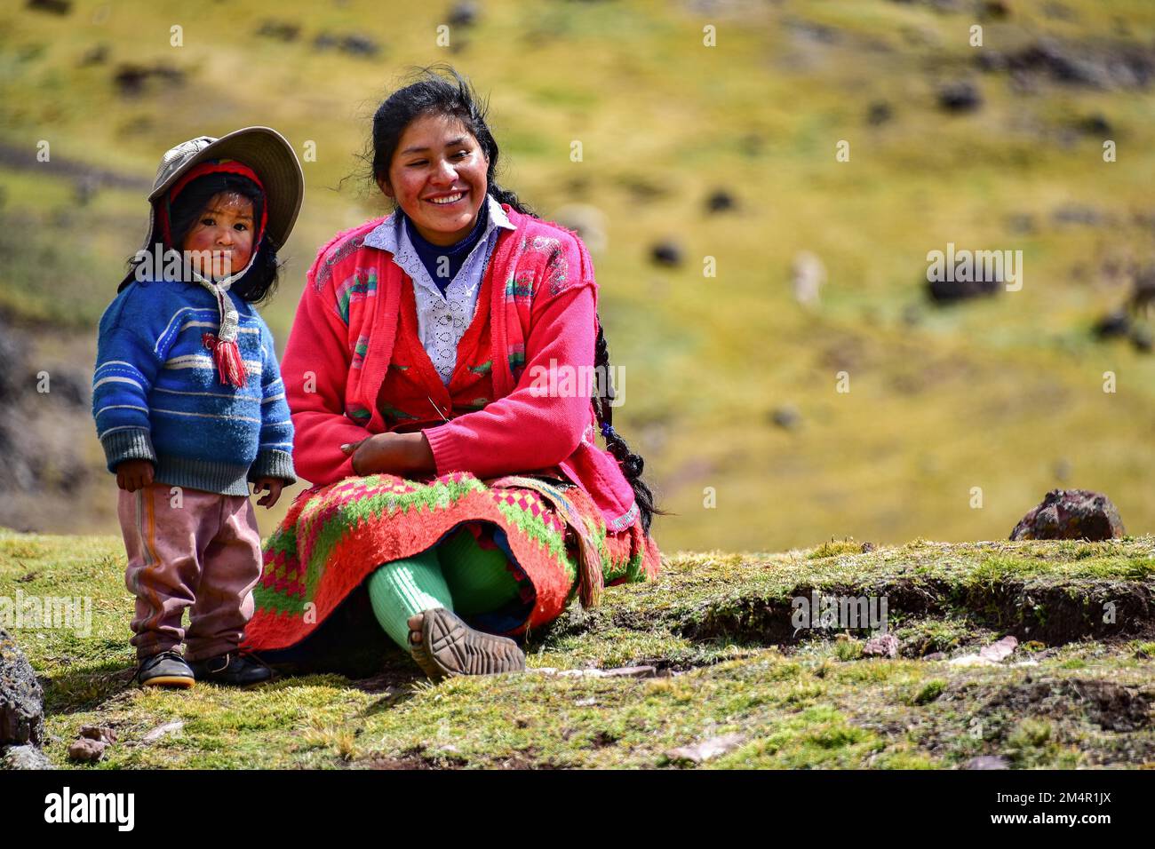 Quechua Indian family in traditional dress sitting in a meadow, Andes ...
