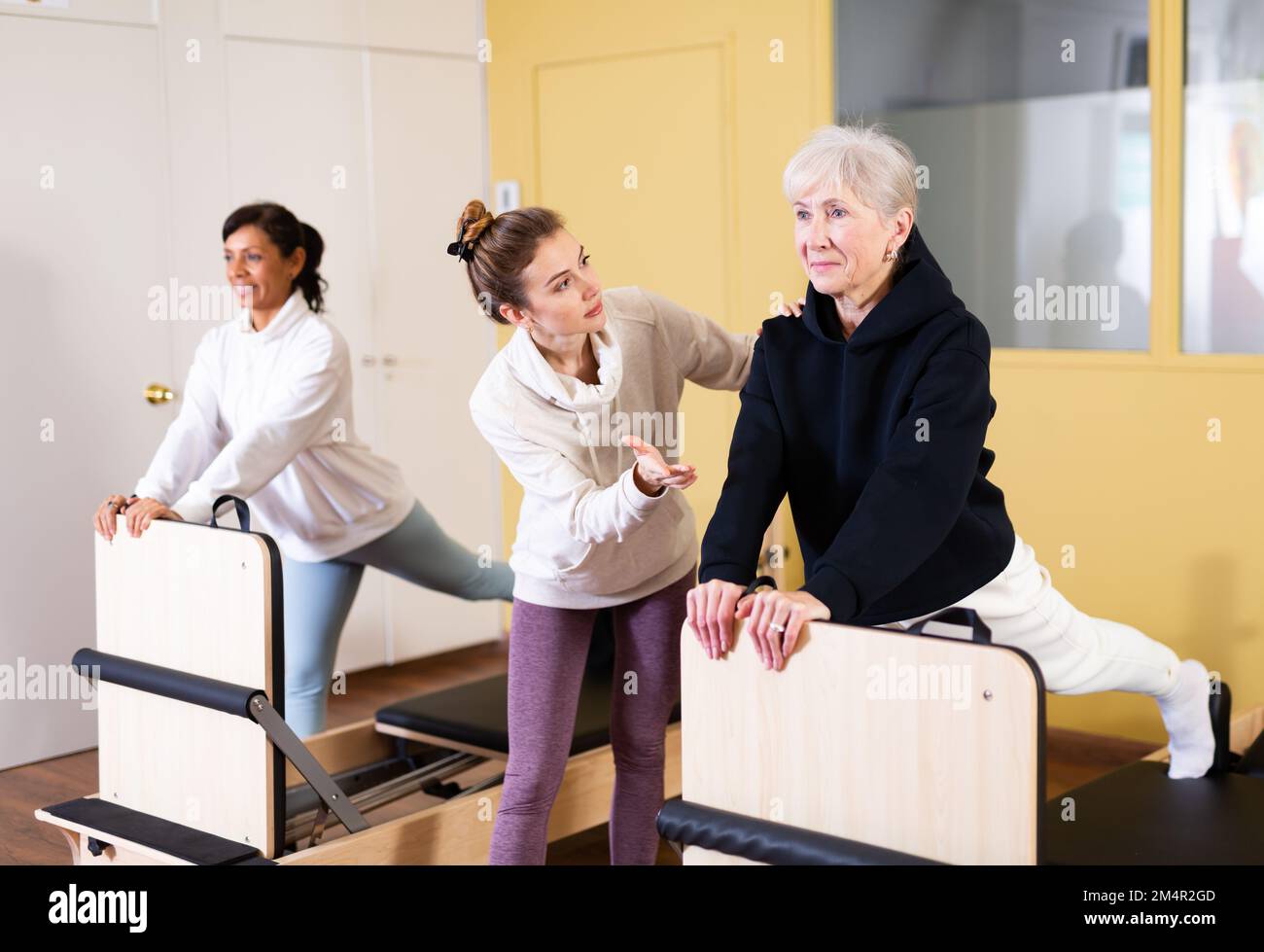 Senior woman exercising on pilates reformer with young trainer Stock ...