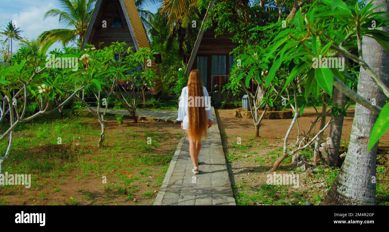 Beautiful rear view of girl with red long hair walks in tropical ...