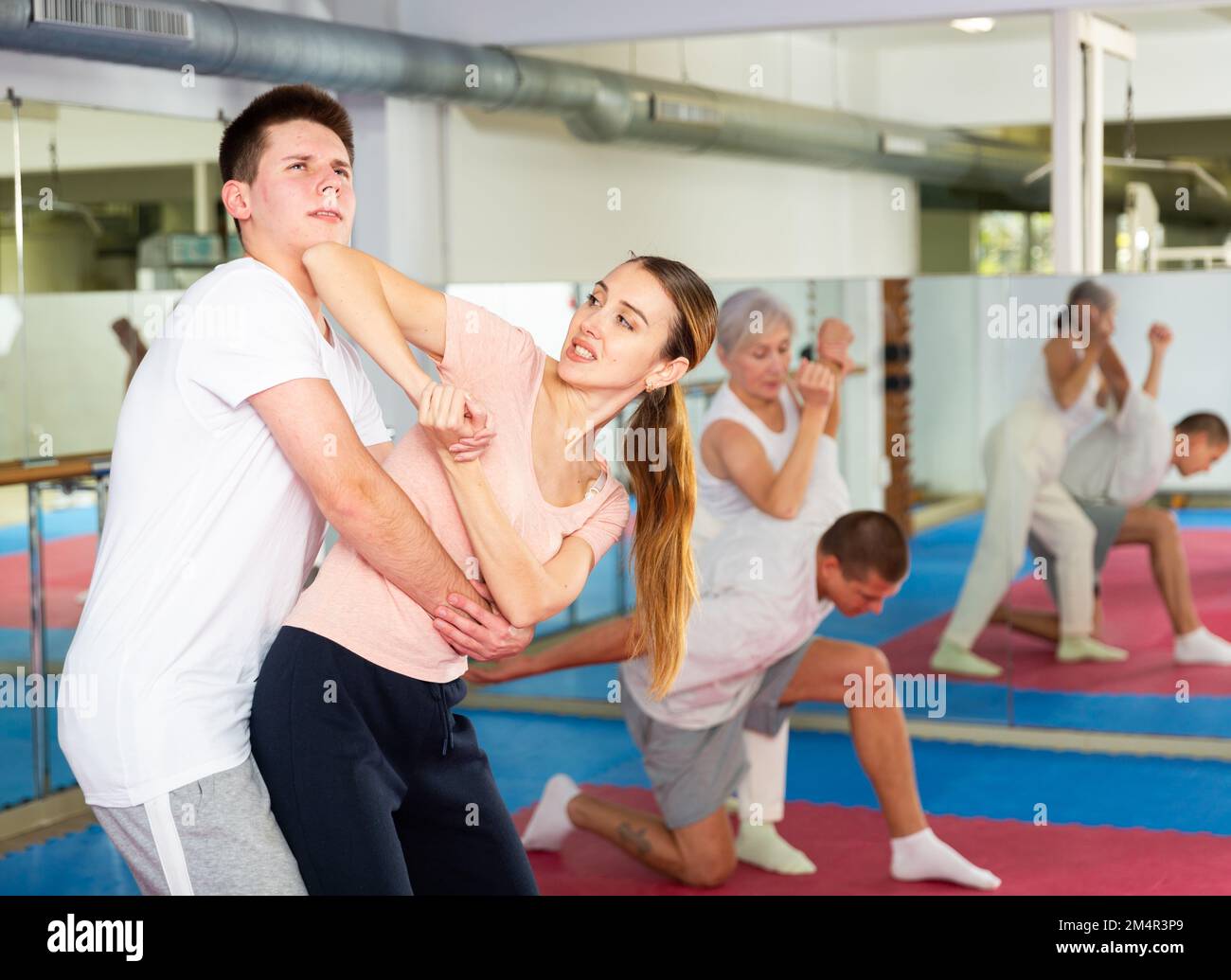 Young woman with male partner practicing basic elbow kick to chin ...