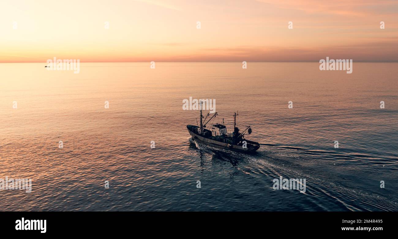 Fishing boat catching fish at sunset aerial view from drone. Small ...
