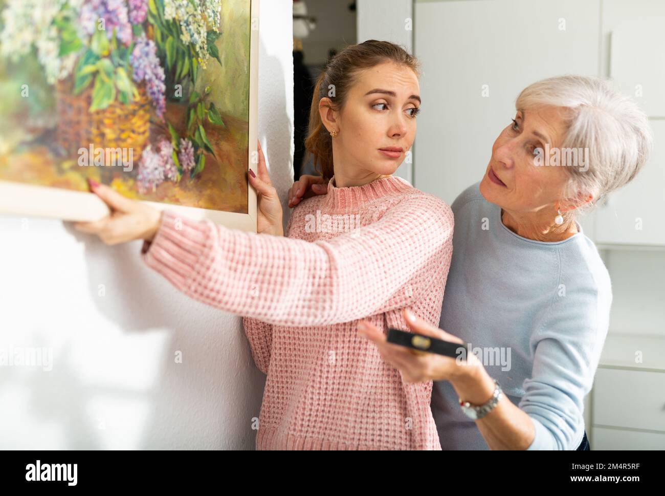 Mother and daughter putting picture on wall Stock Photo - Alamy