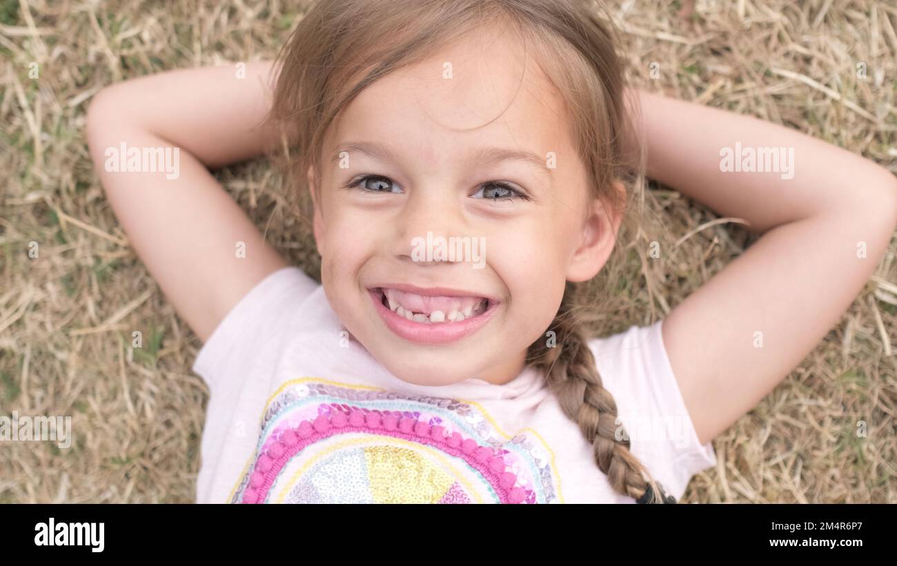 Little Happy toothless and Smiling Child Girl Laying on Yellow Lawn Dry ...